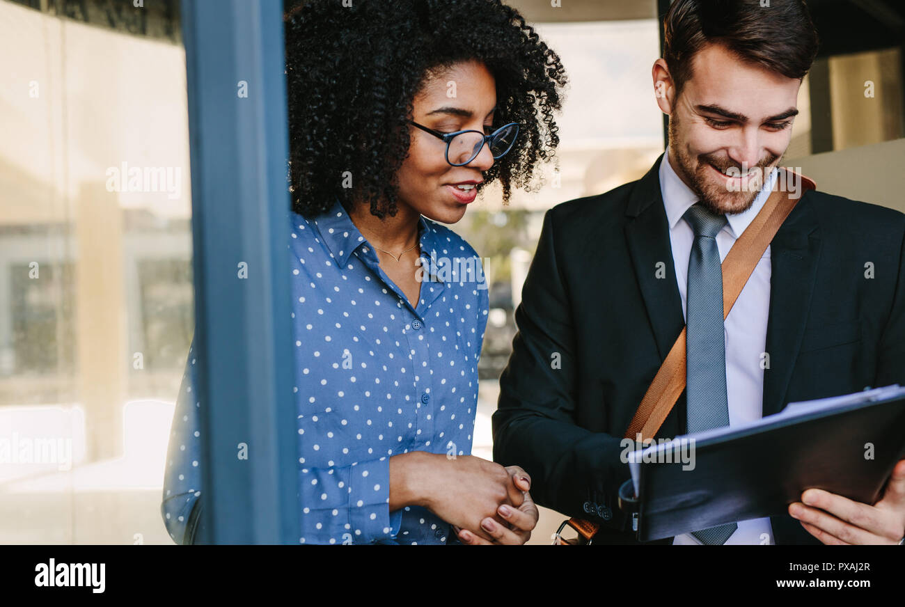 Two business professionals looking at a file and smiling. Office ...
