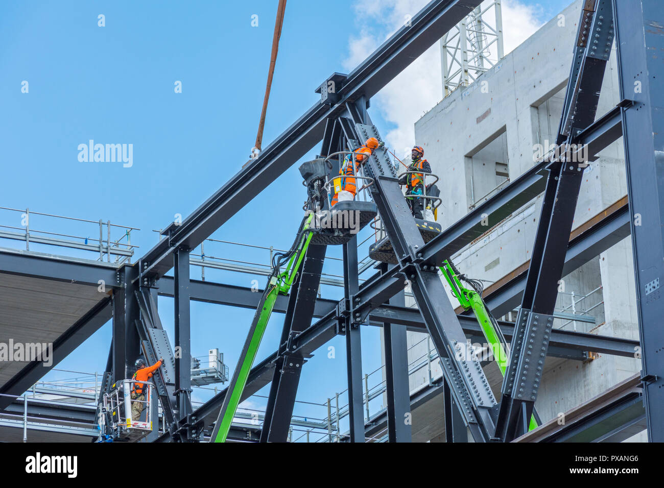 Workmen on aerial platforms erecting steelwork for the Manchester ...