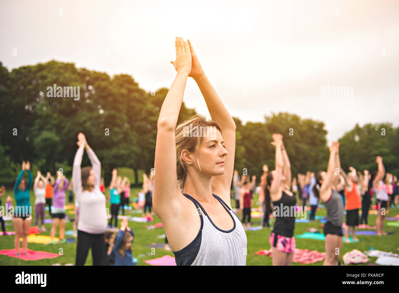A big group of adults attending a yoga class outside in park Stock ...