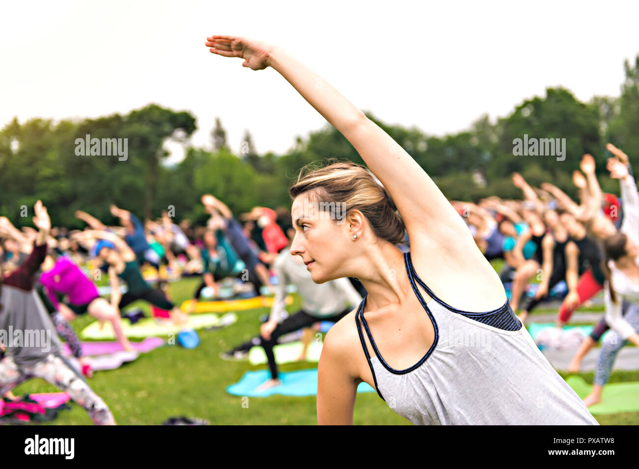A big group of adults attending a yoga class outside in park Stock ...