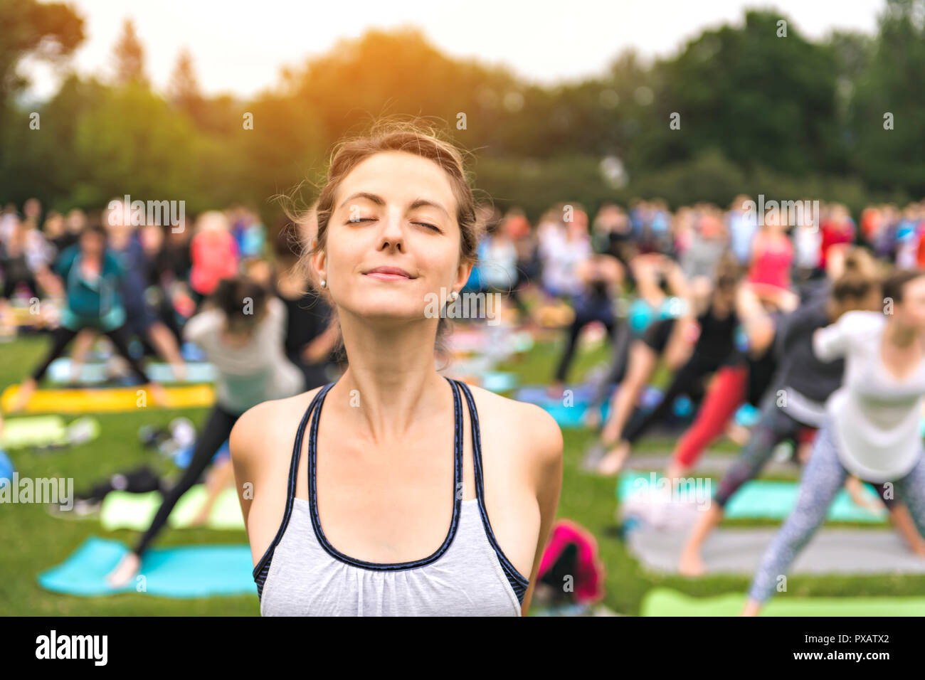 A big group of adults attending a yoga class outside in park Stock ...