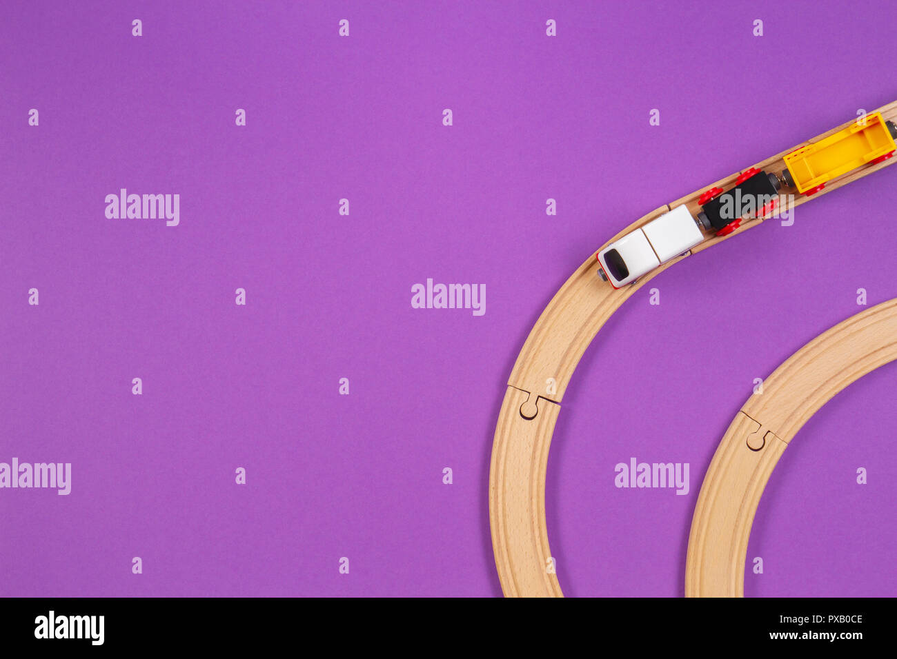 Toy train and wooden rails on purple violet background Stock Photo - Alamy