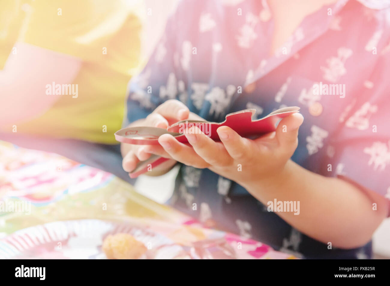 The child is holding small children's symbols cut out of paper. The ...