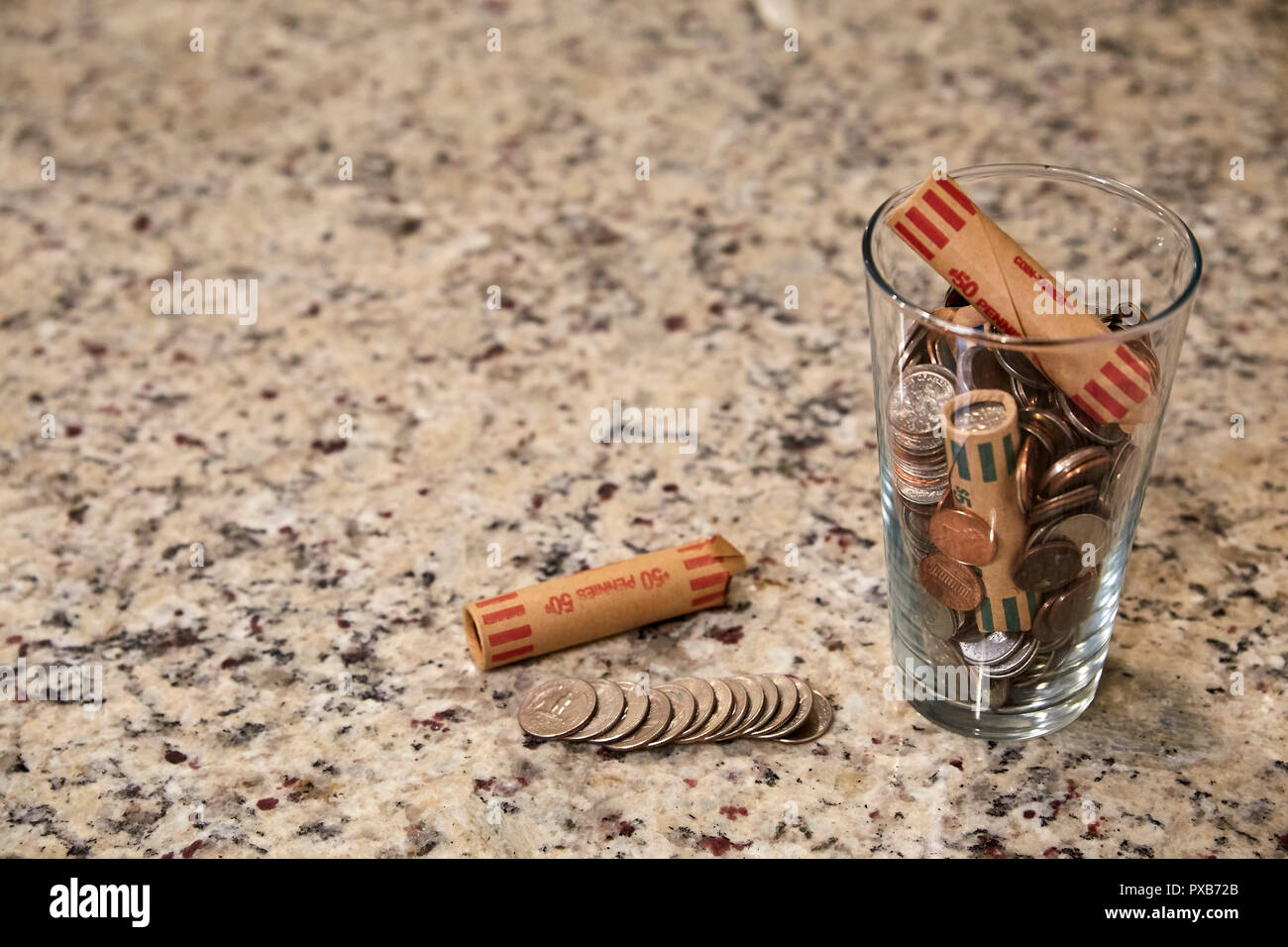 Glass jar of coins in cup on desk money savings debt bank rich poor ...