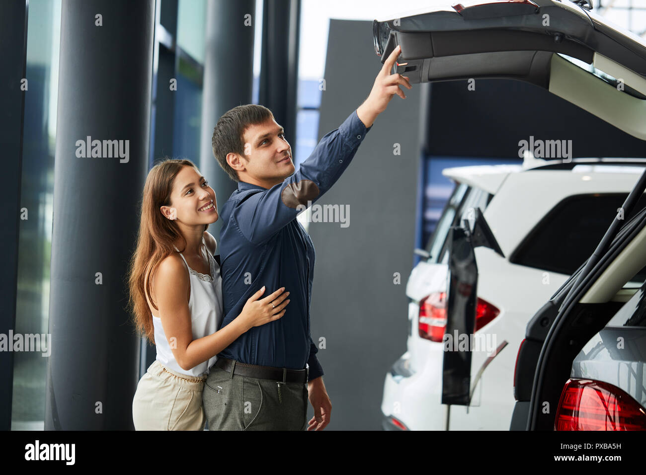 Loving smart couple choosing a car at the car dealership showroom Stock ...
