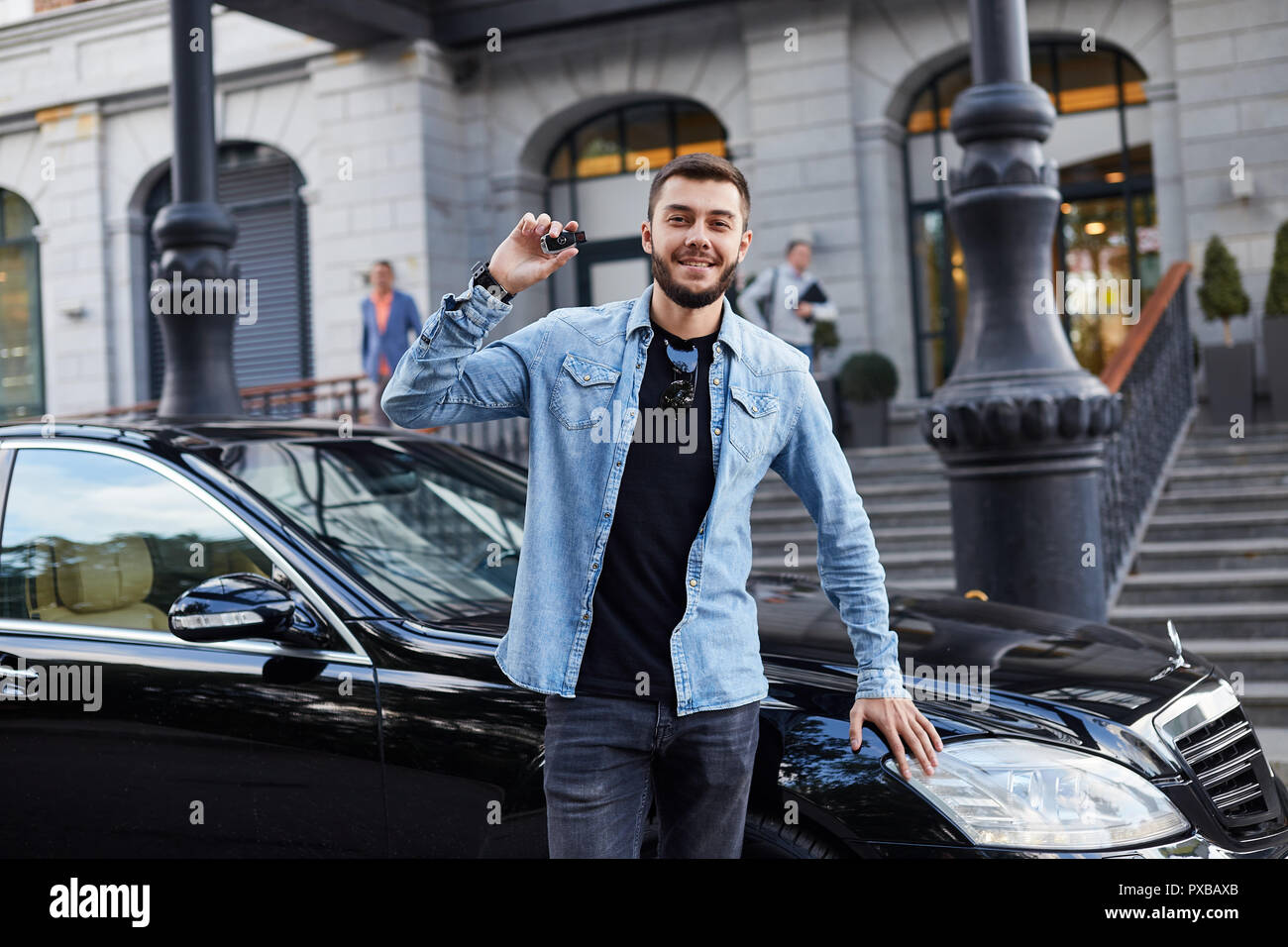 Handsome man standing in front of black car and presenting it Stock ...