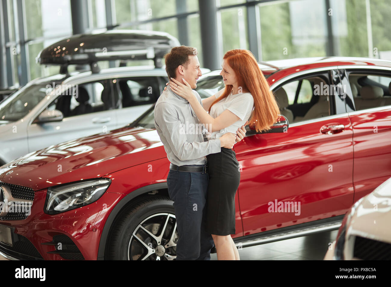Couple hugging while buying first new family car together in dealership ...