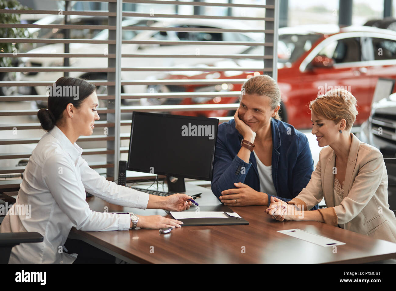 Beautiful young couple signs documents at dealership showroom Stock ...