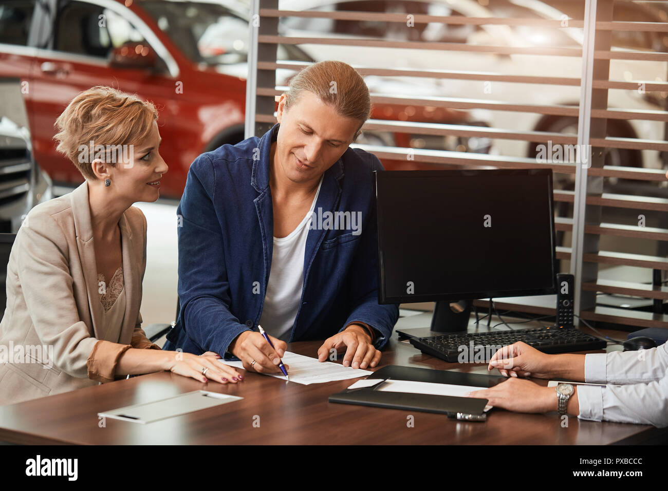 Happy beautiful couple is buying a new car at dealership. Family ...