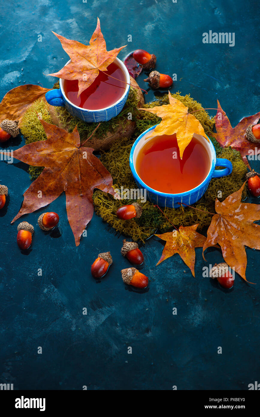 Autumn tea with a blue handmade ceramic cup, acorns and fallen maple ...