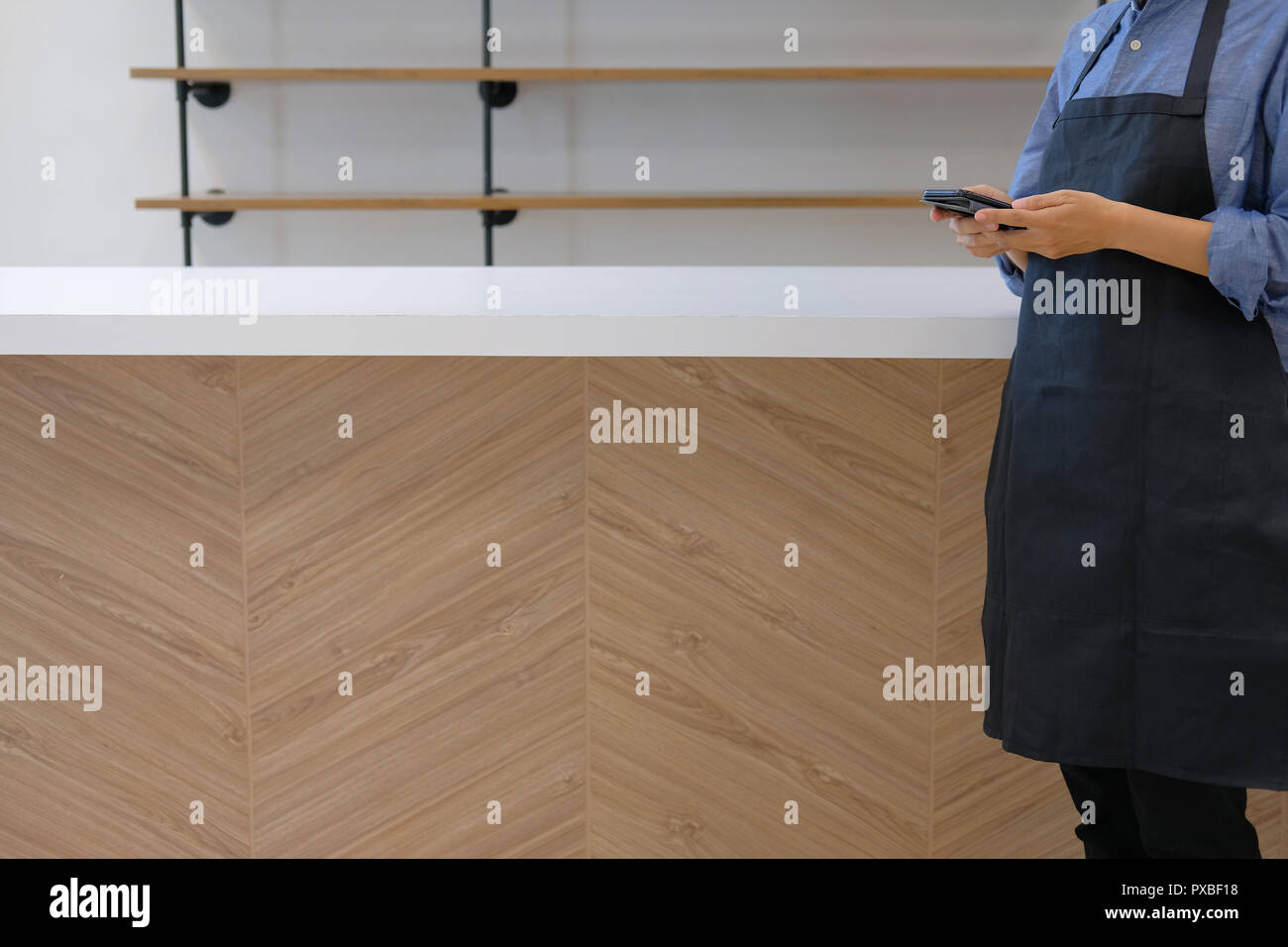 business owner wearing apron holding mobile phone at counter bar. man ...