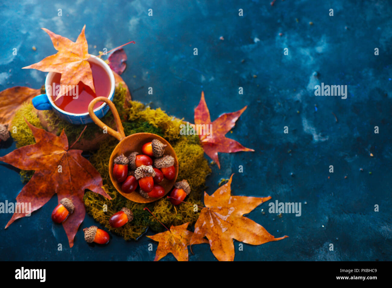Autumn tea header with blue ceramic cup, acorns in a wooden scoop and ...