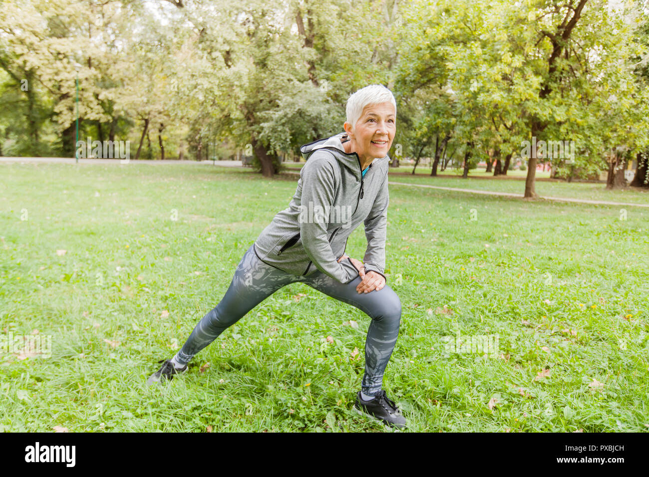 Healthy Middle Aged Woman In Sportswear Stretching Exercise In Nature ...
