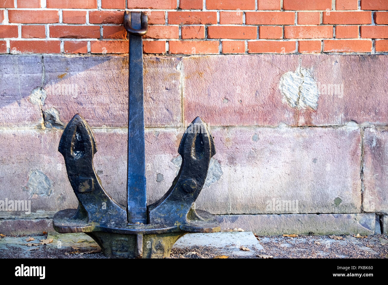 Ancient anchor stands on the ground leaning against the wall Stock ...
