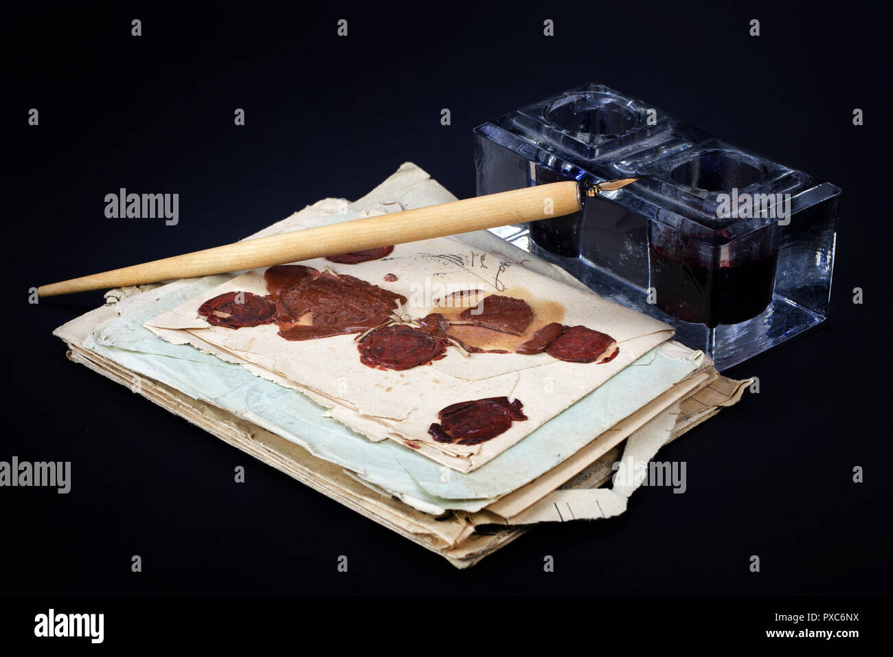 Old fountain pen and inkwell with old letters on a black background ...