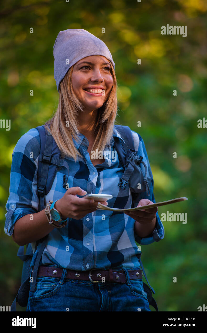 Young woman walking alone in the woods holding a map. Hiking concept in ...