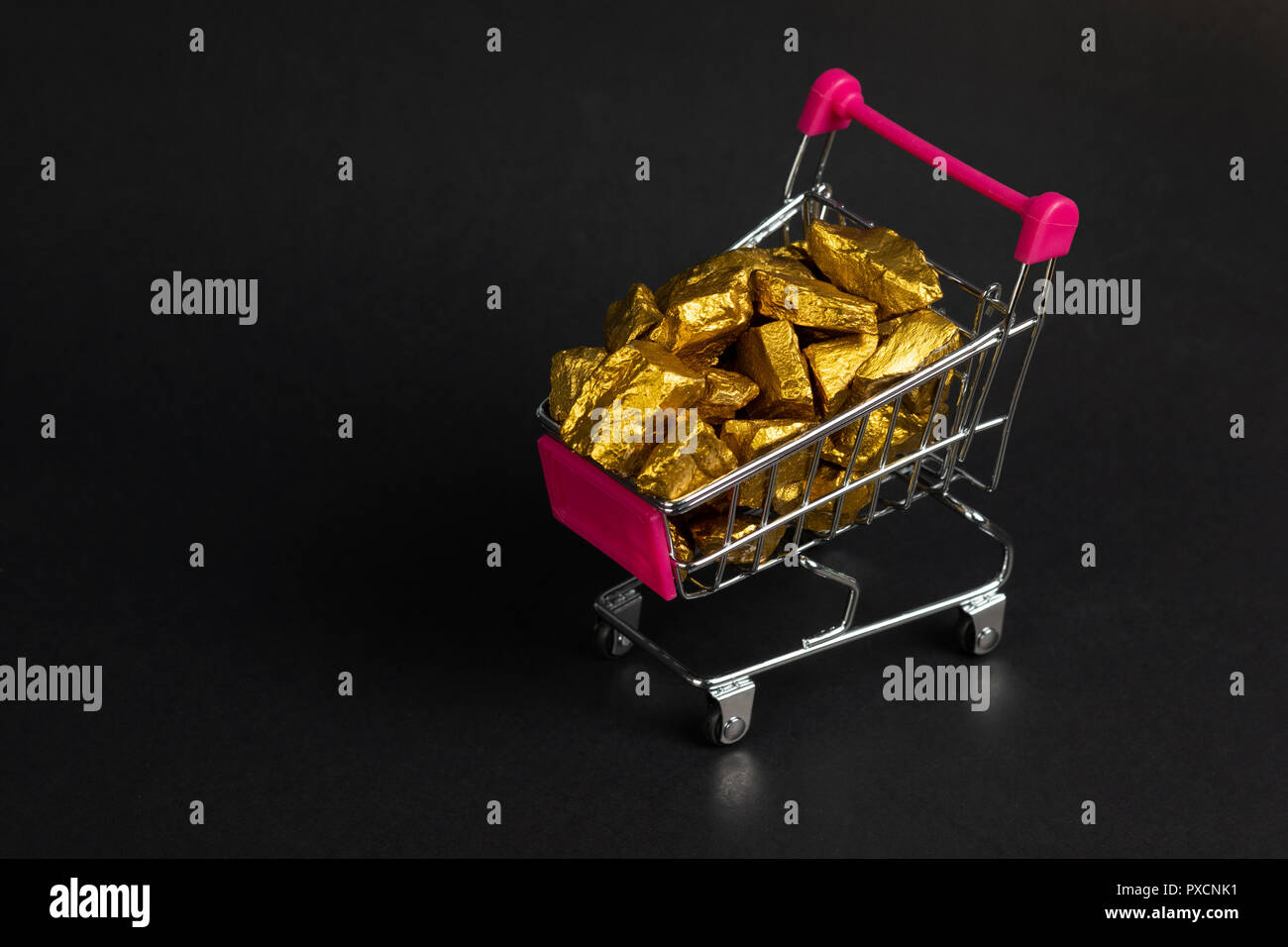A pile of gold nuggets or gold ore in shopping cart or supermarket ...