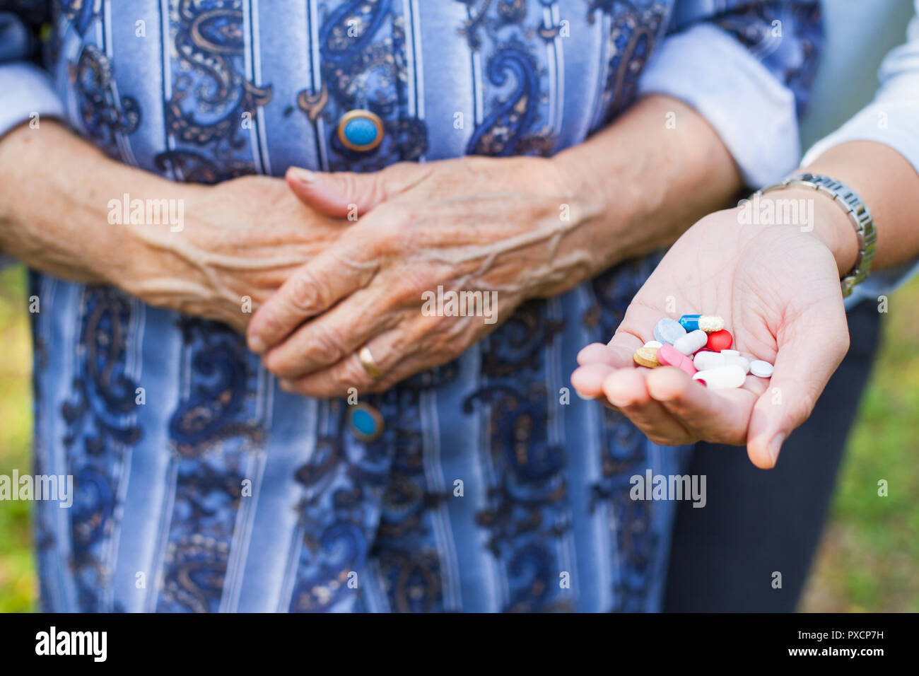 Close up picture of wrinkled elderly hand and a handful of medication ...