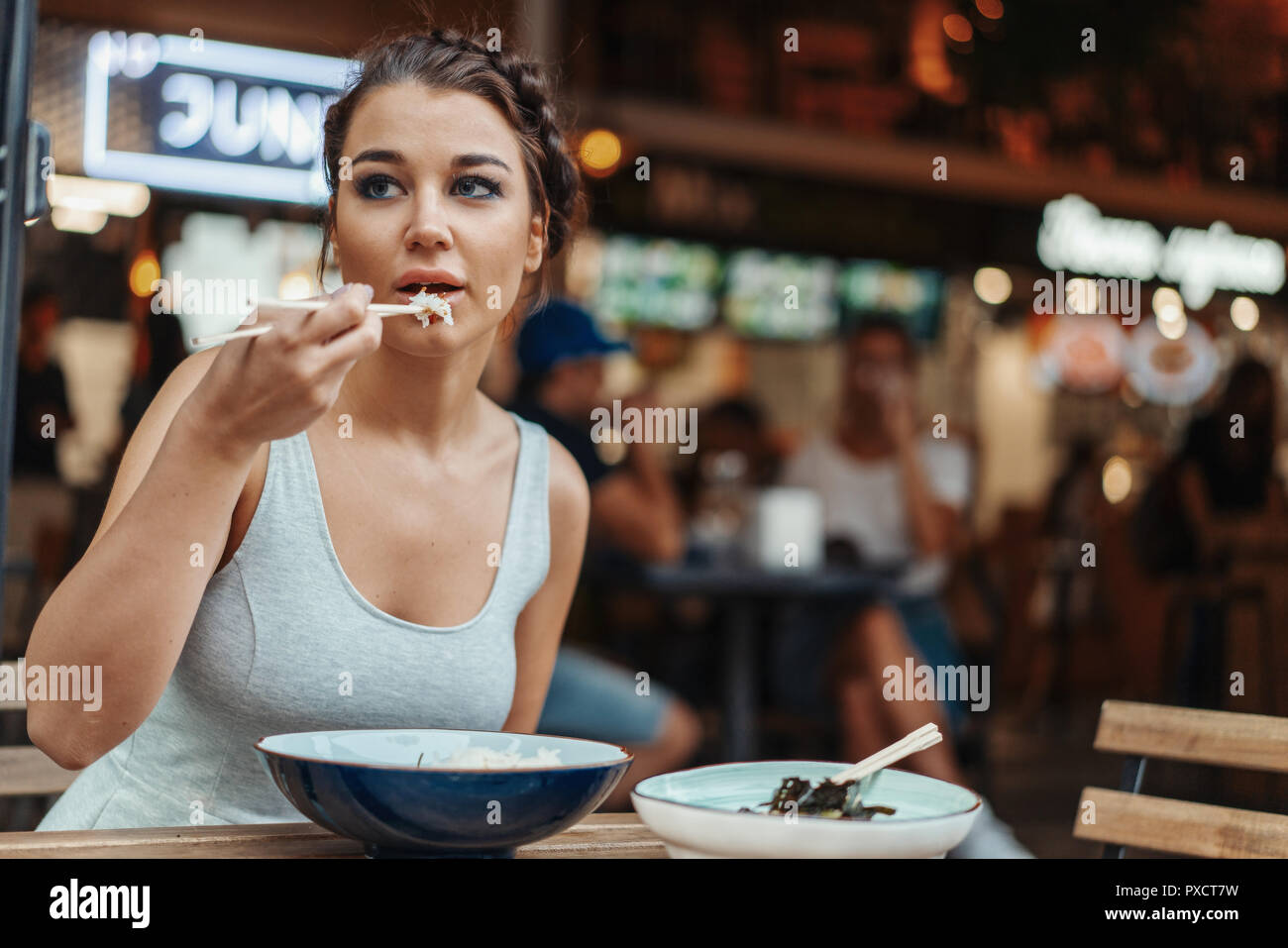 Beautiful woman eating chicken with rice in street cafe of chinese food ...