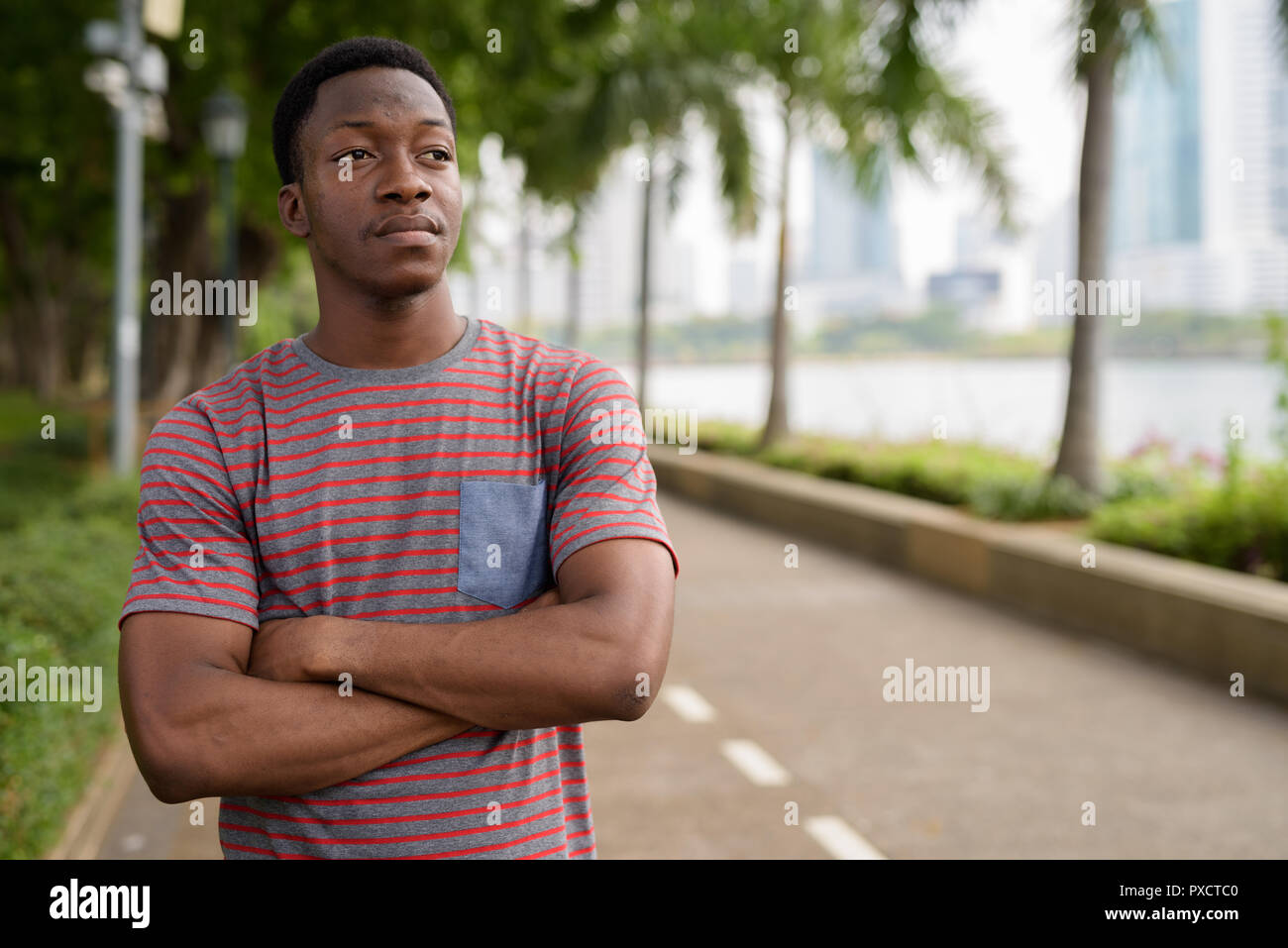 Portrait of young handsome African man relaxing at the park and ...