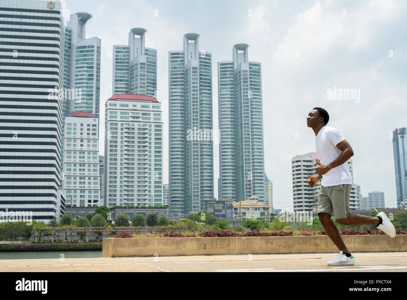 Young African man running outdoors in park with cityscape Stock Photo ...