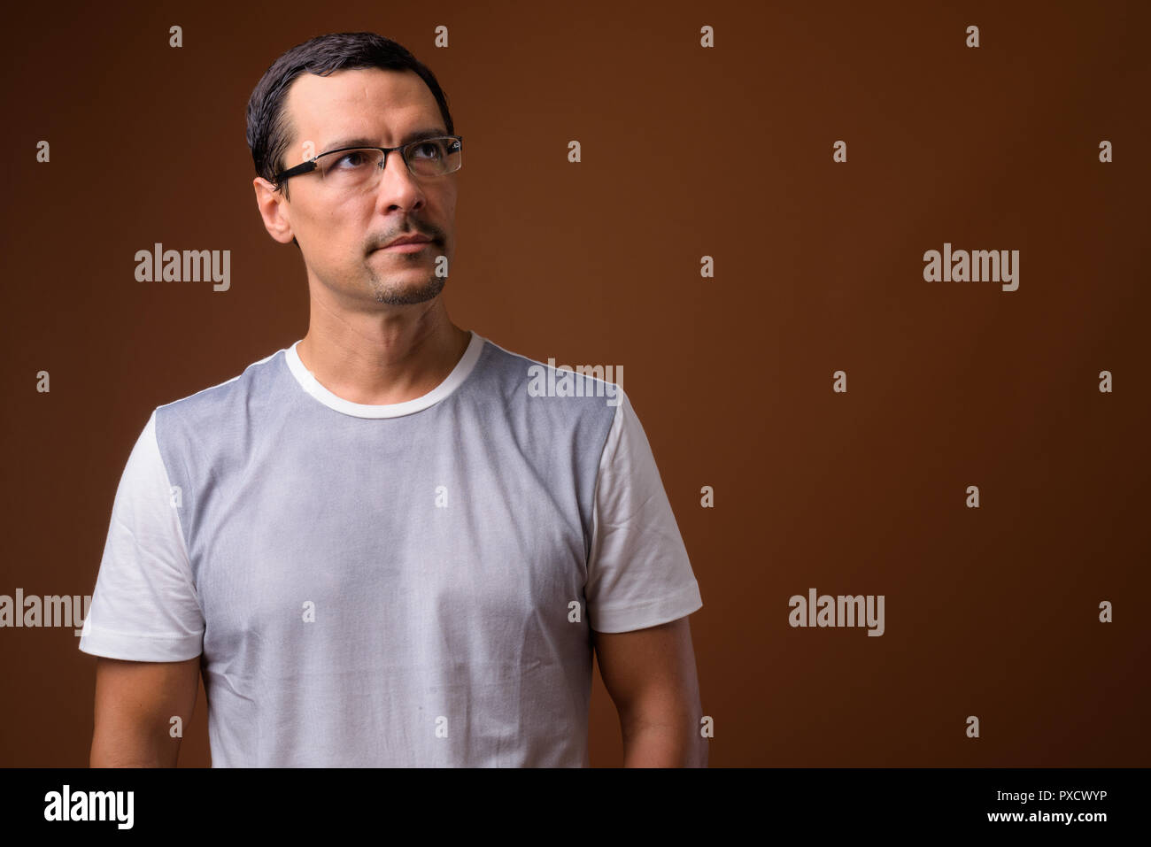 Portrait of handsome man thinking against brown background Stock Photo ...