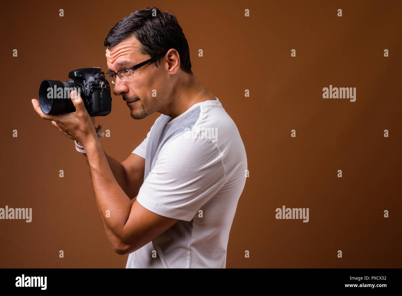 Portrait of photographer man taking picture against brown background ...