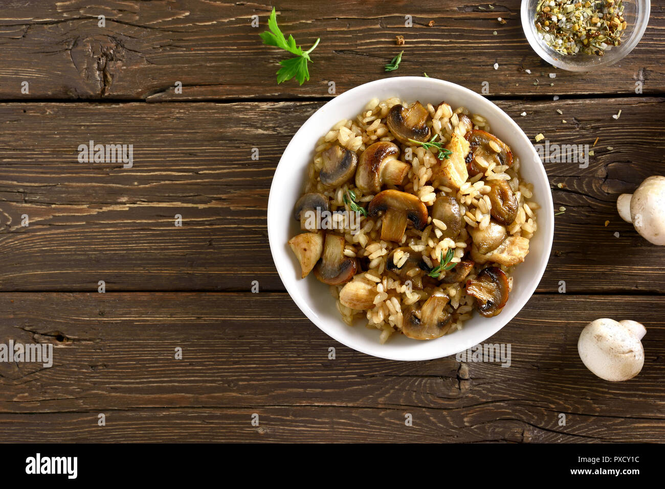 Delicious risotto with mushrooms and pieces of chicken meat on wooden ...