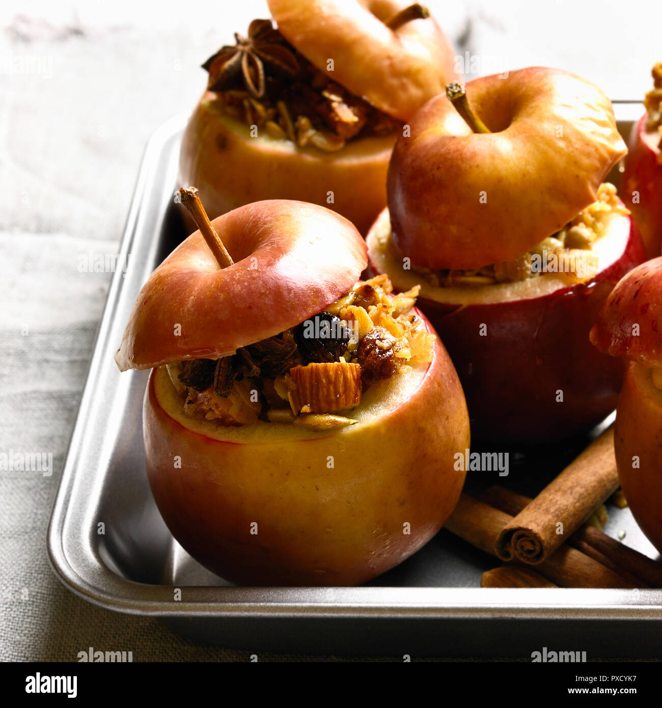 Close up of baked apples with granola, cinnamon, nuts and honey in pan ...