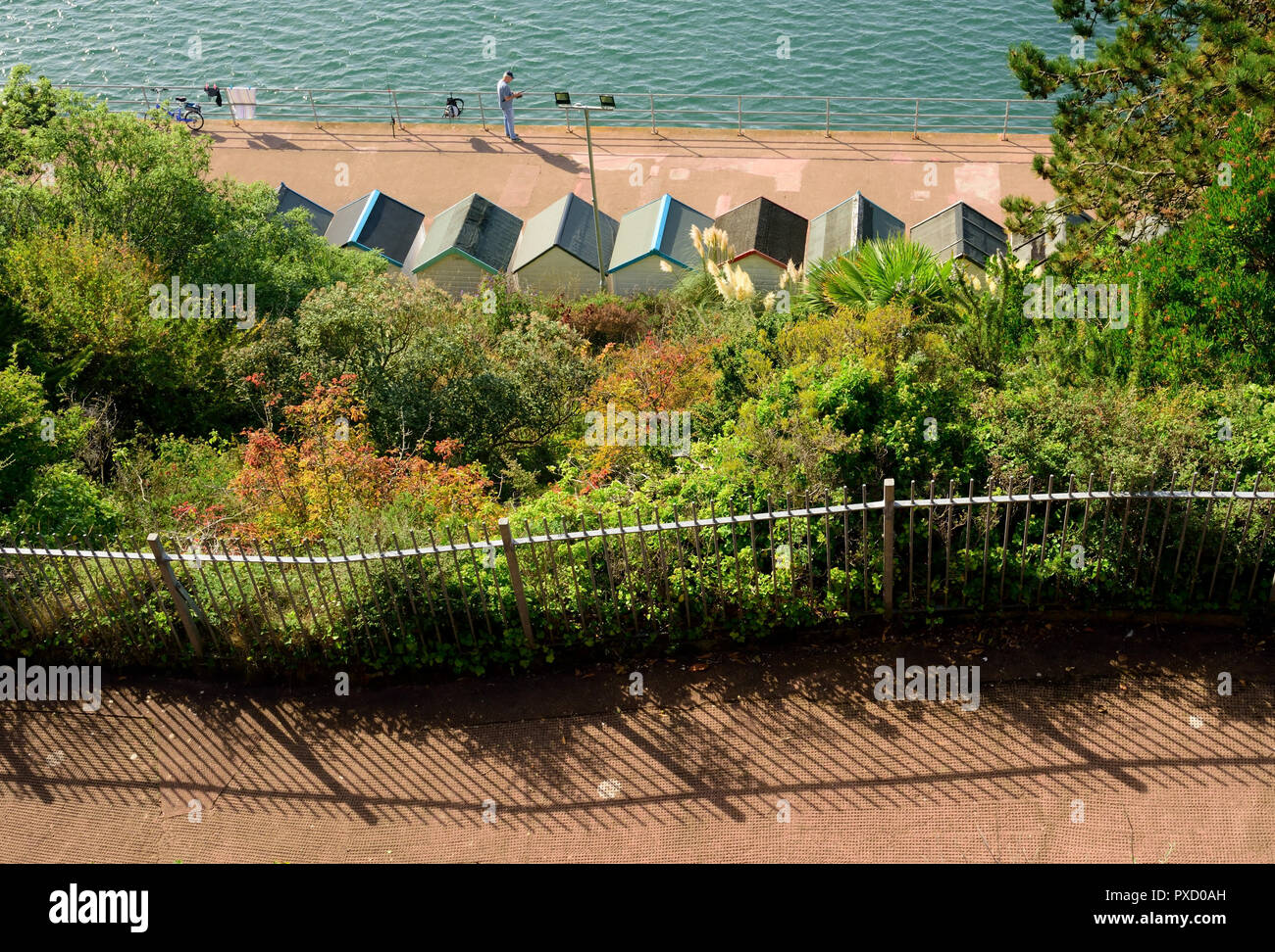 An elevated view of beach huts and a fisherman at Goodrington Stock ...