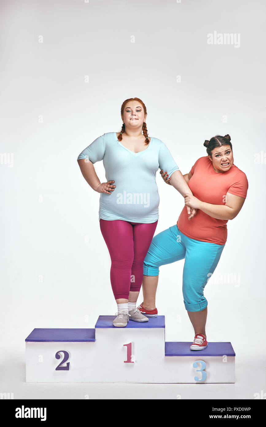 Overweight women are standing on a winner's pedestal isolated on white ...