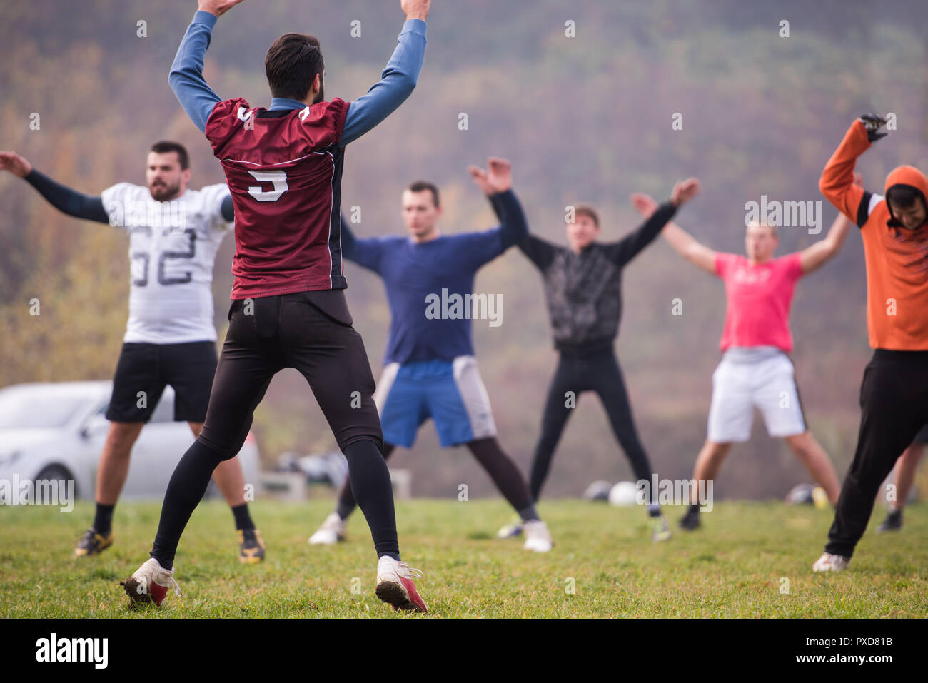 group of young american football players stretching and warming up ...