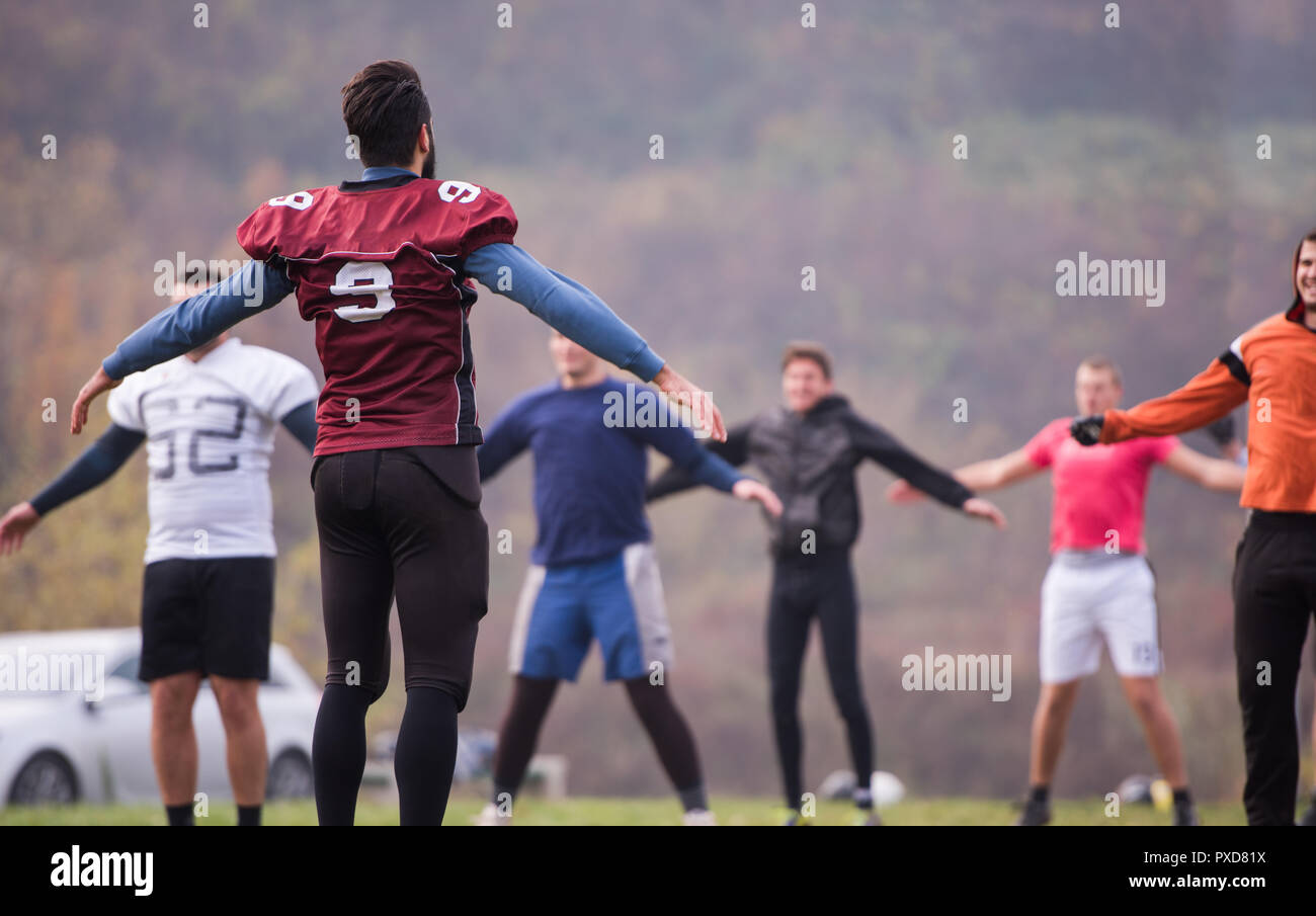 group of young american football players stretching and warming up ...