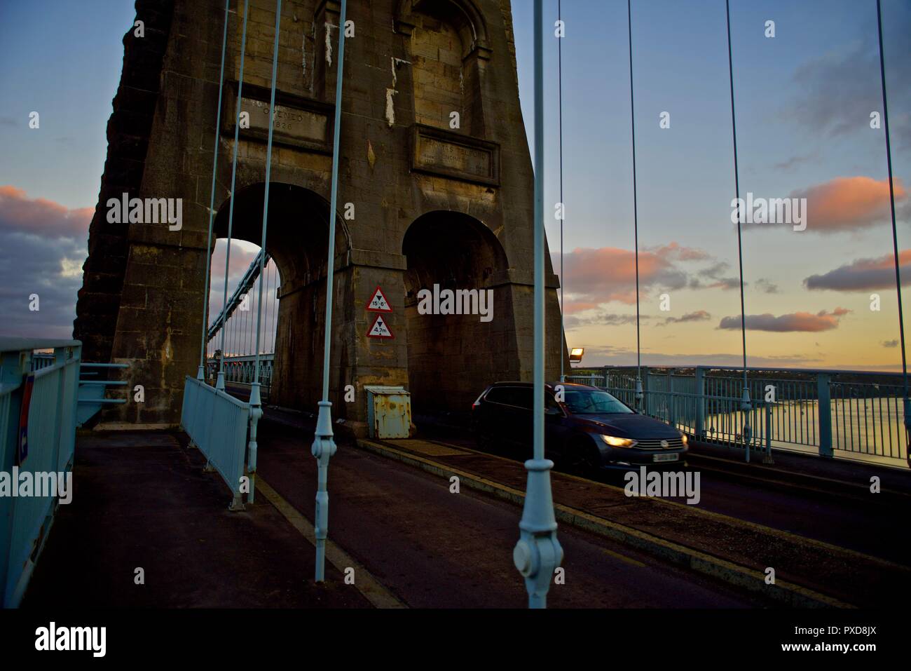 A car crosses the Menai Suspension Bridge at dawn, Bangor, Wales, UK ...