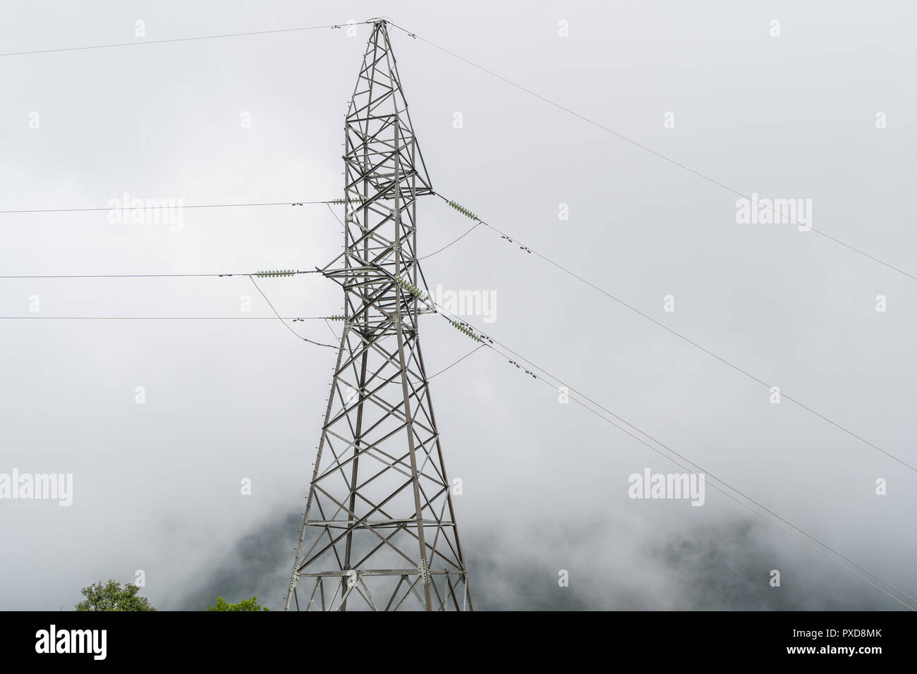 High voltage pole towers on the mountain in the fog and mist on forest ...