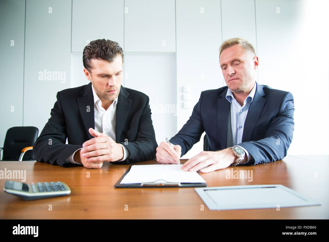 Two business people signing a document at conference table Stock Photo ...