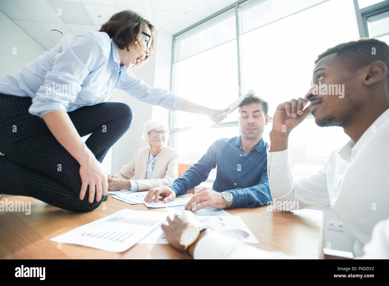 Furious employee hitting boss with rolled paper Stock Photo - Alamy