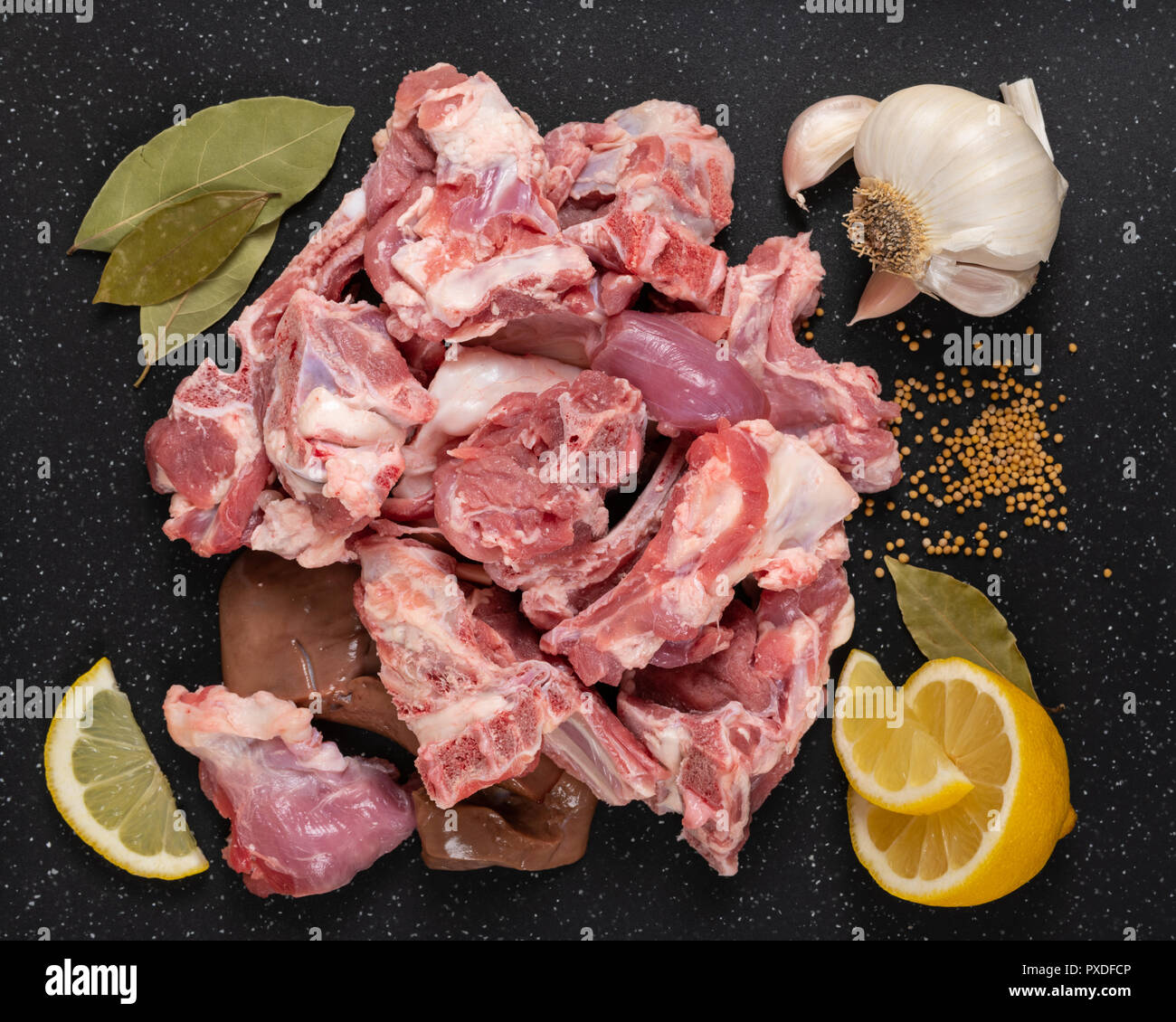 Fresh raw goat meat stew like cuts on black cutting board with spices ...