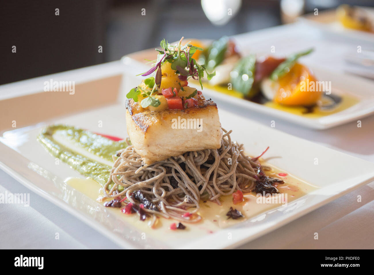 Grilled fish on a bed of seasoned pasta with salsa and garnish Stock ...