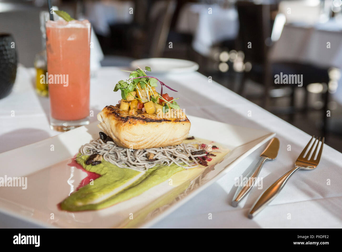 Grilled fish on a bed of seasoned pasta with salsa and garnish Stock ...