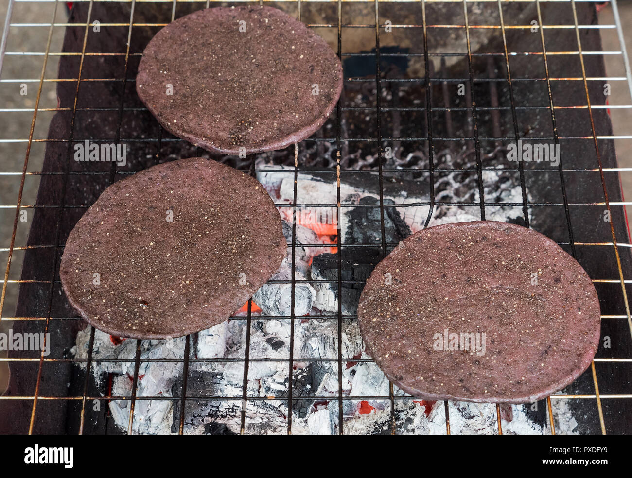 Black sticky rice with sesame seeds in a mortar is roasted on the stove ...