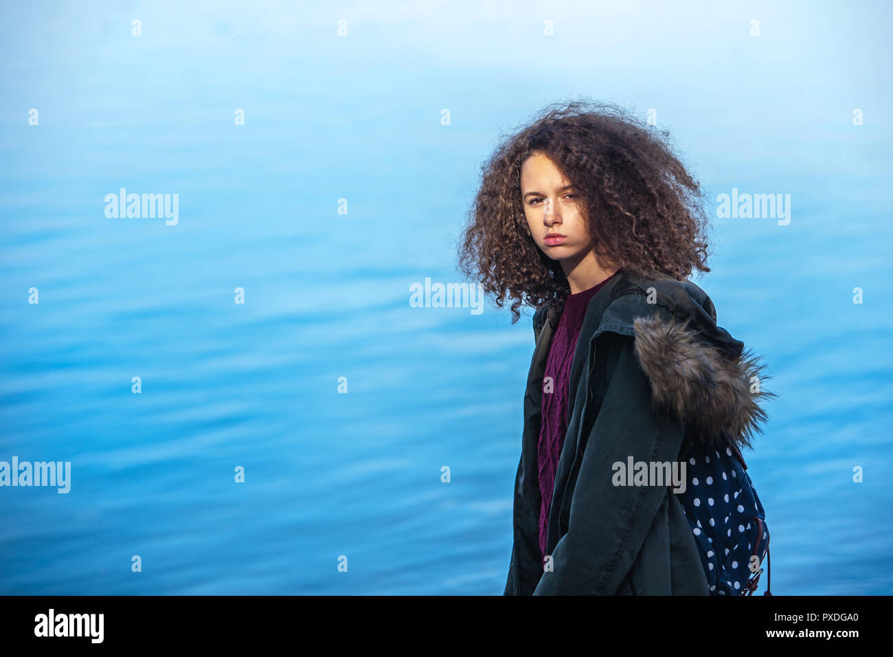 Portrait of curly hair teen girl standing by the river Stock Photo - Alamy