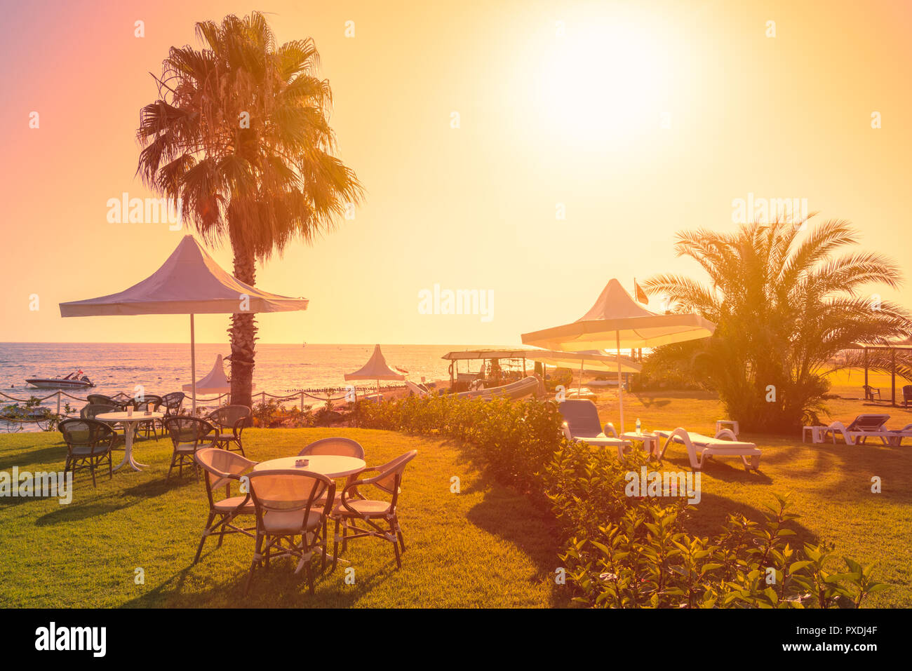 Beach in Turkey with green grass in foreground, white sun shade ...