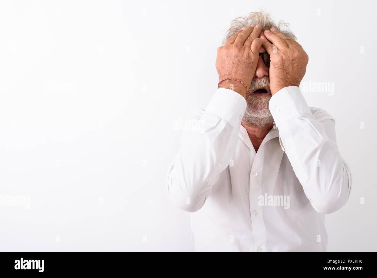Studio shot of senior bearded man looking scared while covering Stock ...