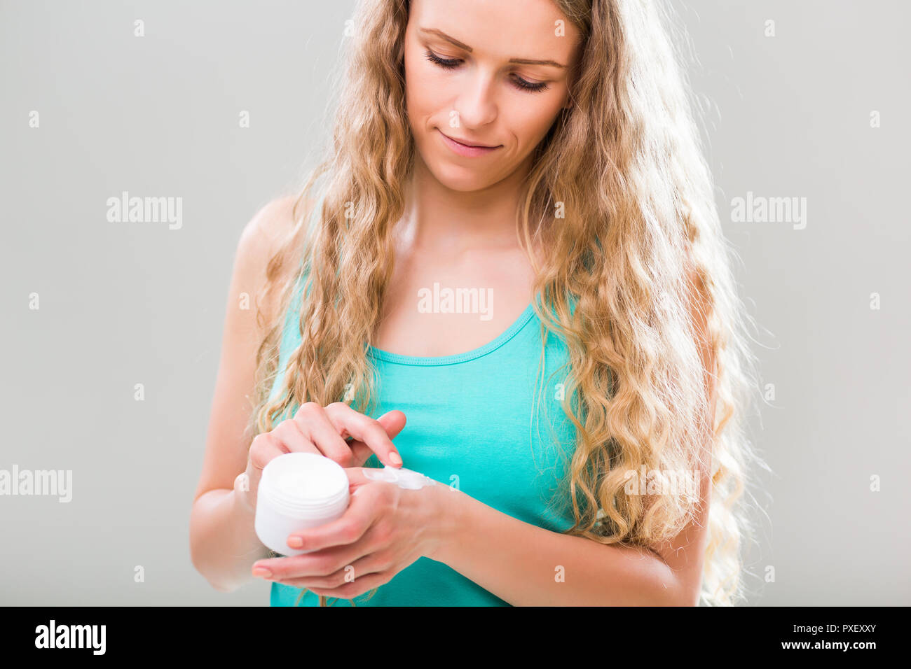 Beautiful young woman applying hand cream on gray background Stock ...