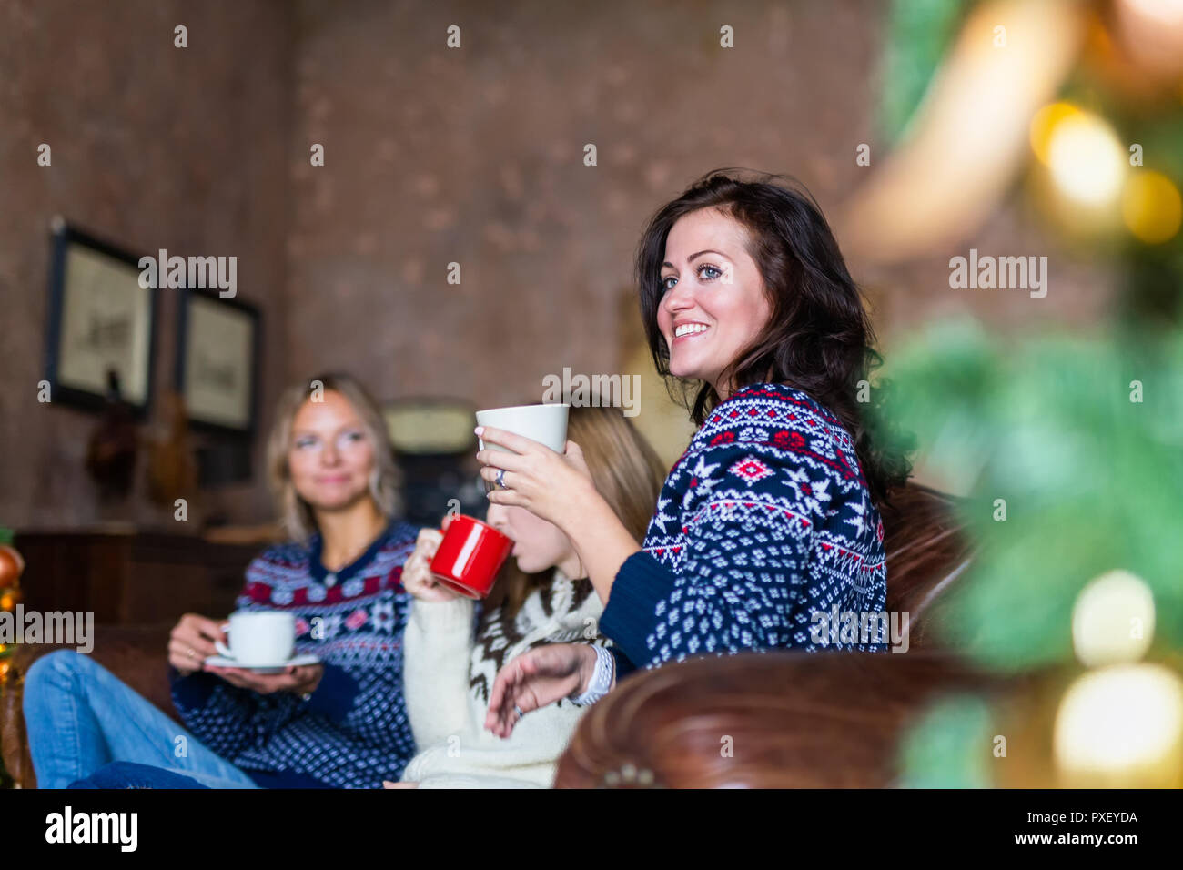 Woman drinking coffee while sitting on a couch with her friends Stock ...