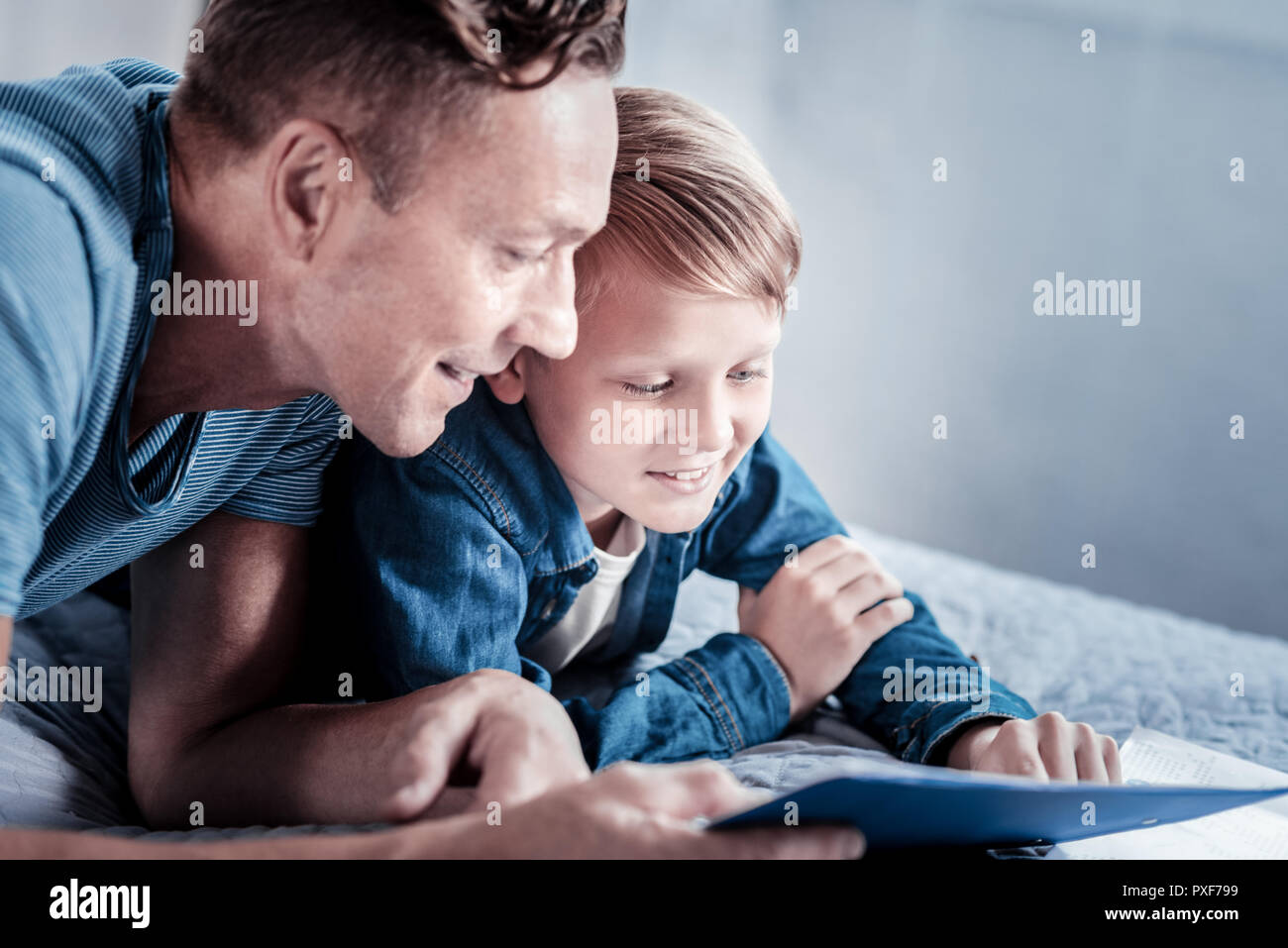 Satisfied pleasant father lying and communicating with son Stock Photo ...