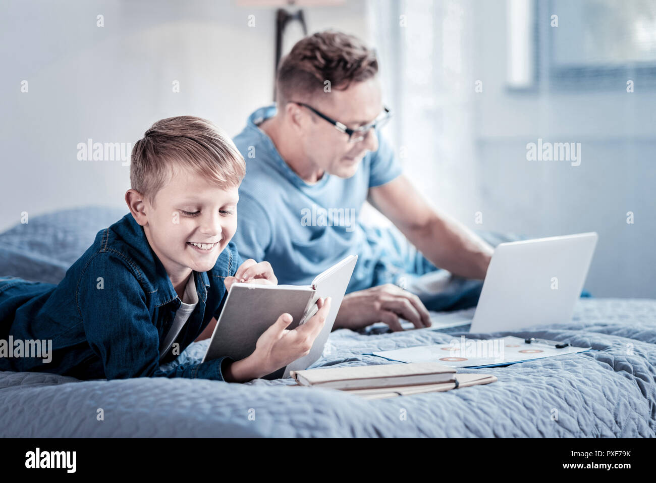 Funny pleasant boy lying and reading the notebook Stock Photo - Alamy