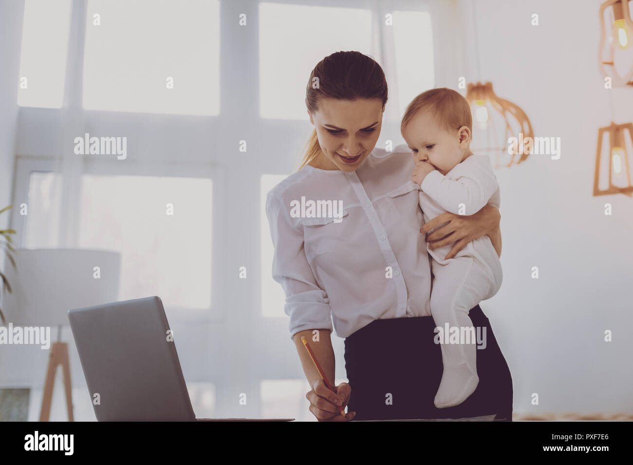 Fashion designer on maternity leave drawing sketches while holding baby ...