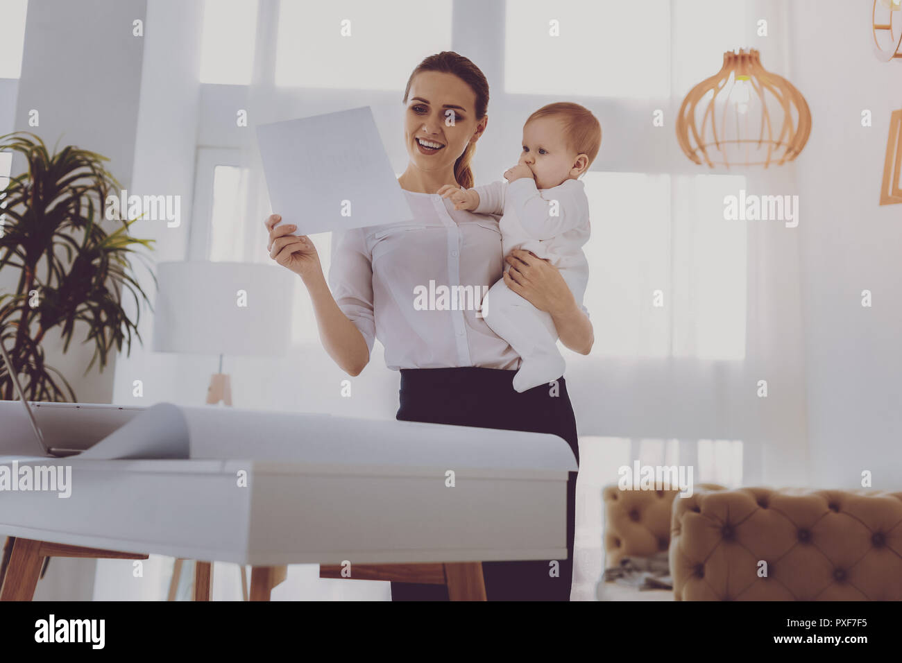 Caring charming mother showing her sweet baby entertaining pictures ...